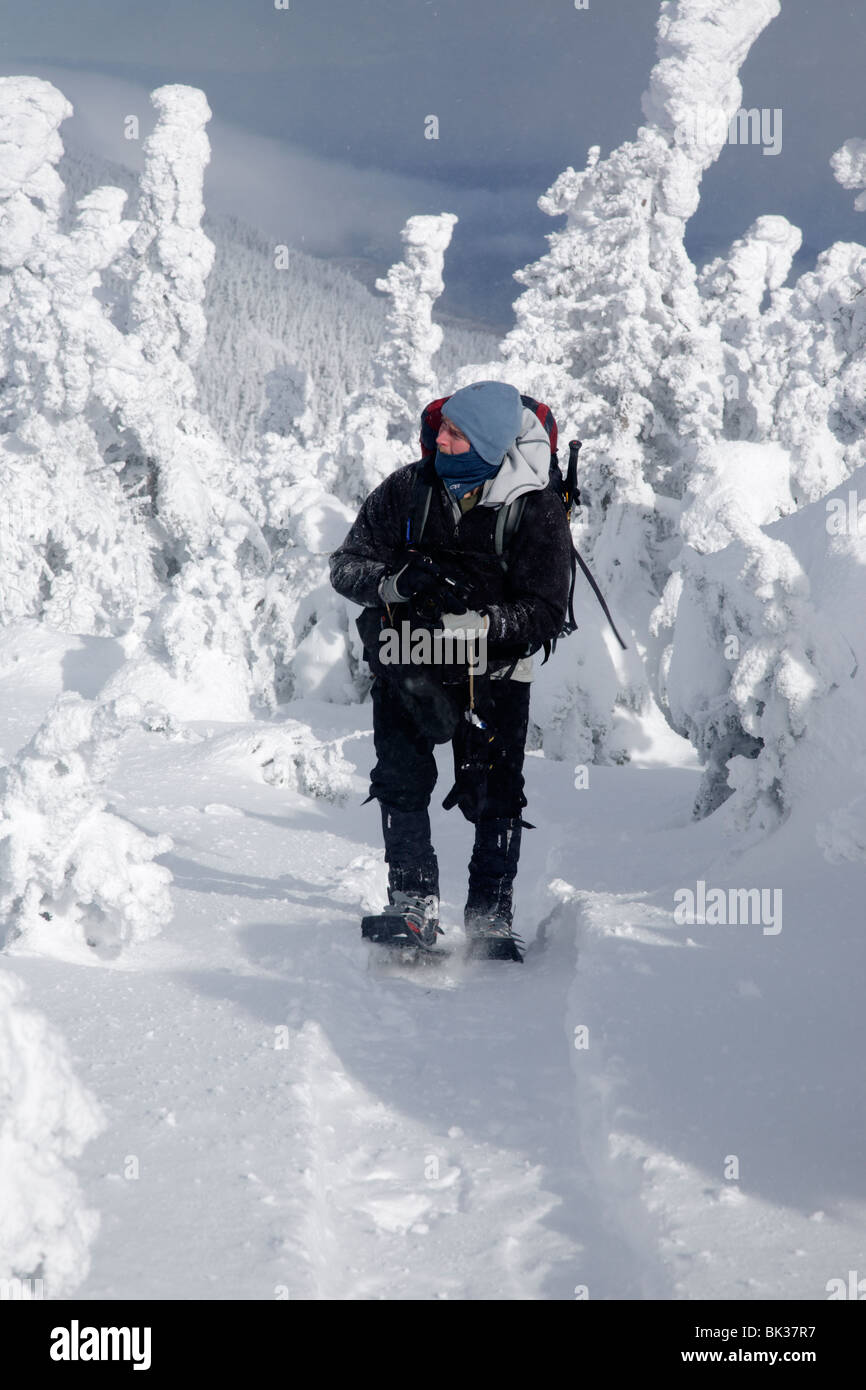 A hiker photographing along the Carter-Moriah Trail in winter ...
