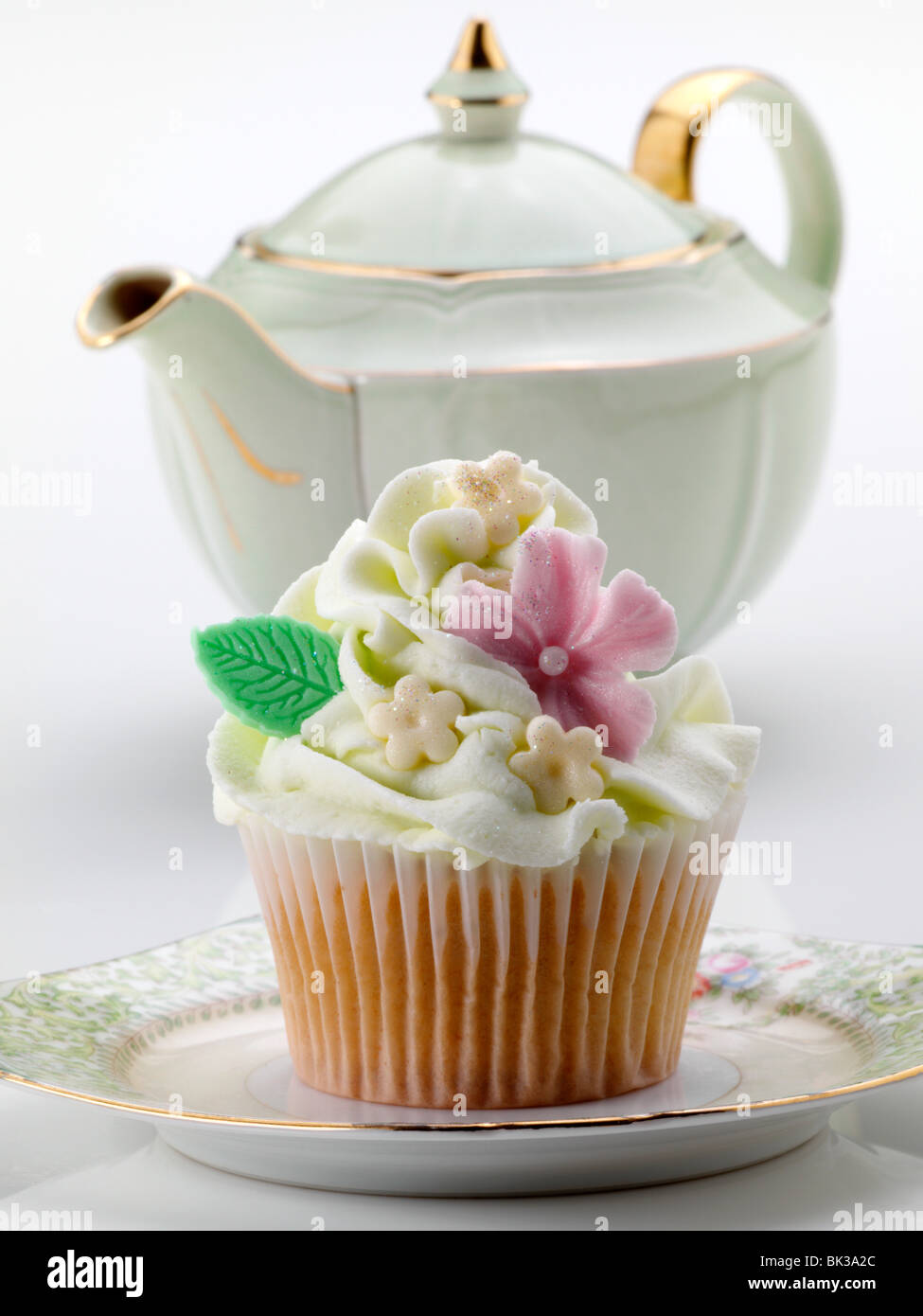 Flower iced cupcake and green teapot Stock Photo - Alamy