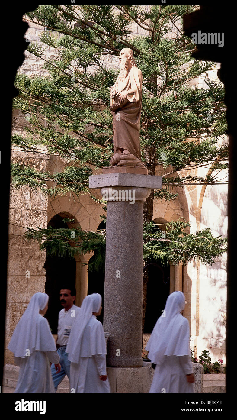 Roman Catholic nuns in white habits walking by statue of Saint Jerome ...