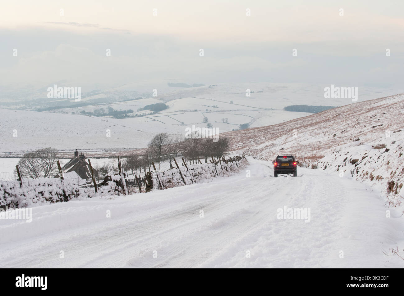 Four-wheel drive vehicle on snow covered road, Peak District ...