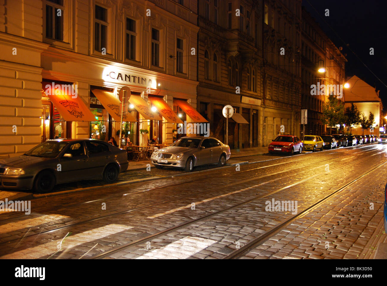 Prague street with tram lines at night: cars, cafe, lights Stock Photo ...