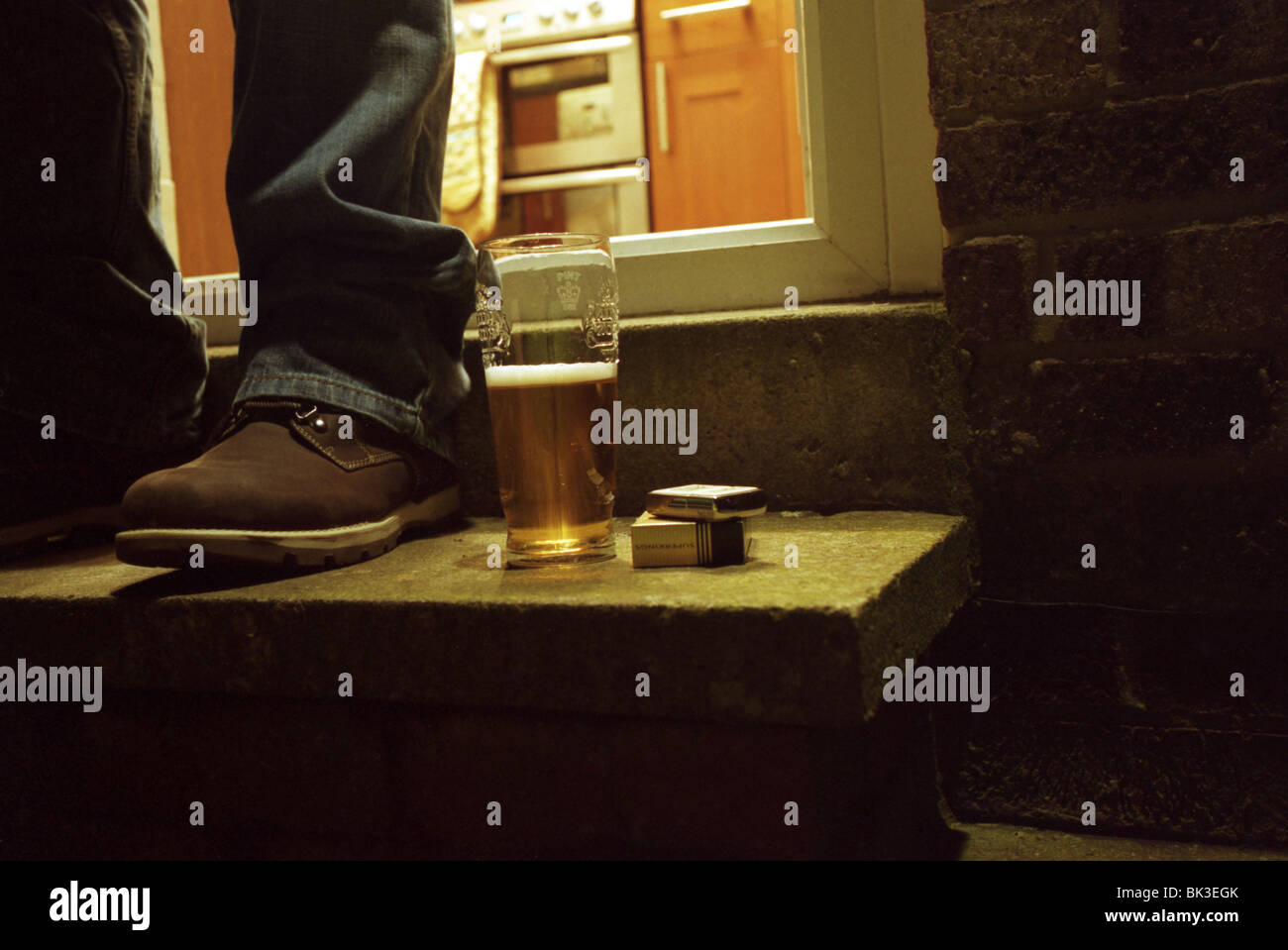 Man standing on doorstep smoking and drinking Stock Photo - Alamy