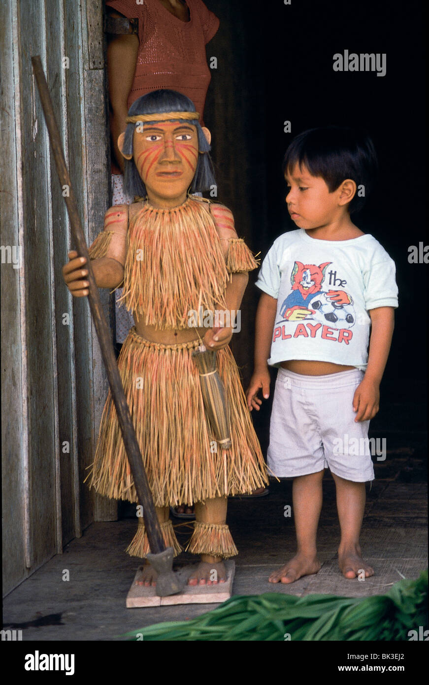 Young Peruvian boy wearing a soccer t-shirt standing next to a carved ...