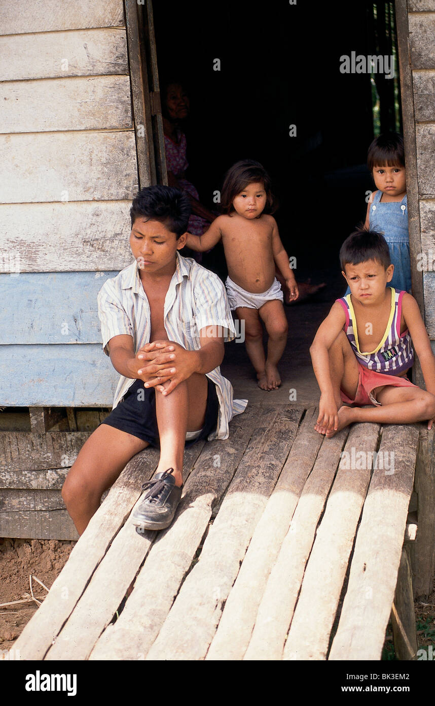 Peruvian children sitting in the doorway of a home in the Amazon Region ...