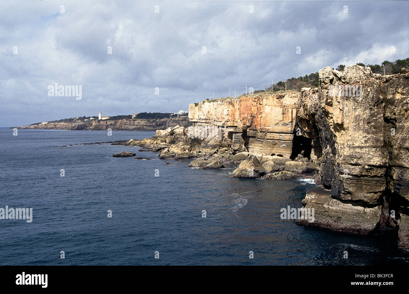 Coastal sandstone cliffs and lighthouse along the Atlantic Ocean coast at Cabo Espichel ...