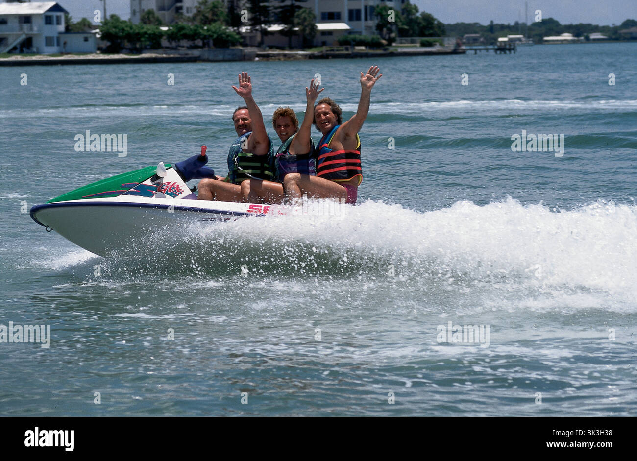 Three people wearing life jackets (personal flotation devices) and ...