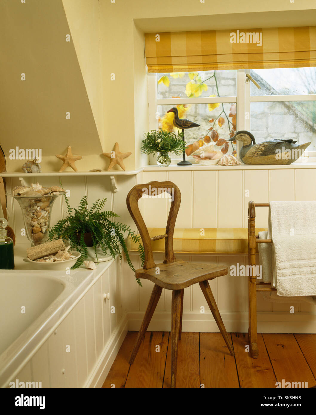 Antique wooden chair below window with yellow checked blind in attic ...