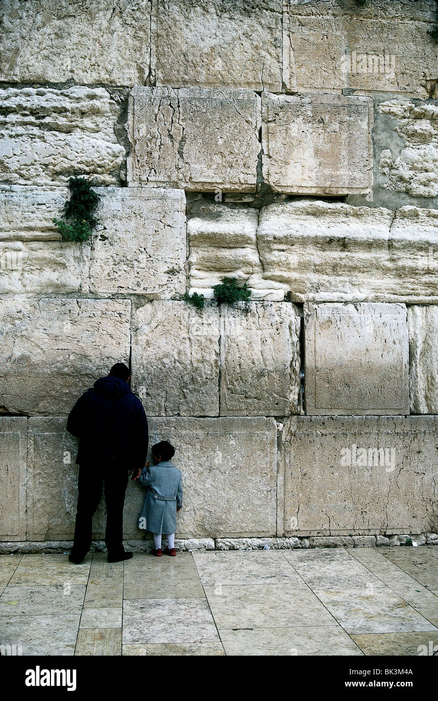 Man and child praying at the Western Wall. The wall, which qualifies as ...