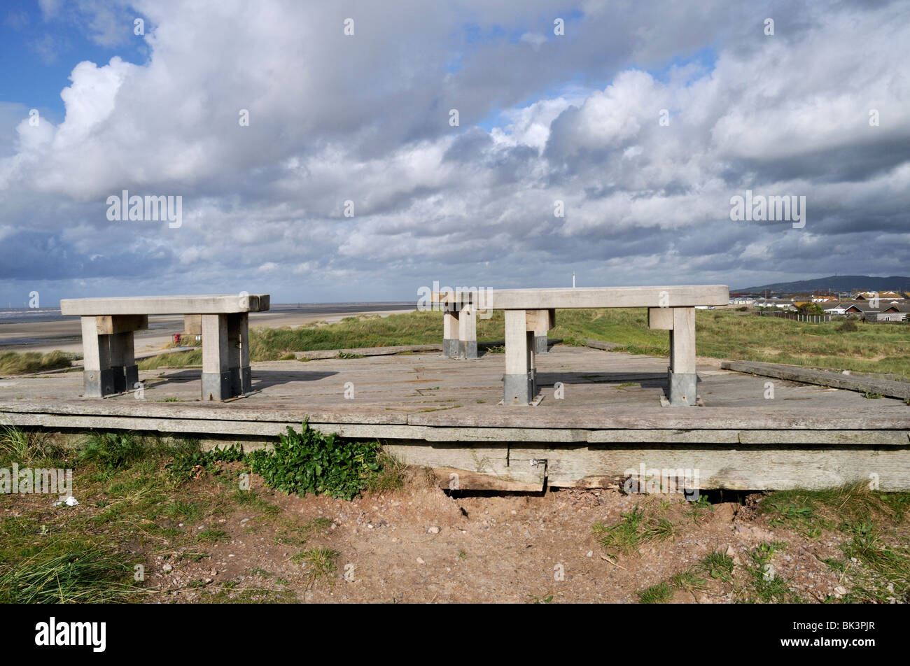 A simple wooden platform built on the beach with a table and benches to ...