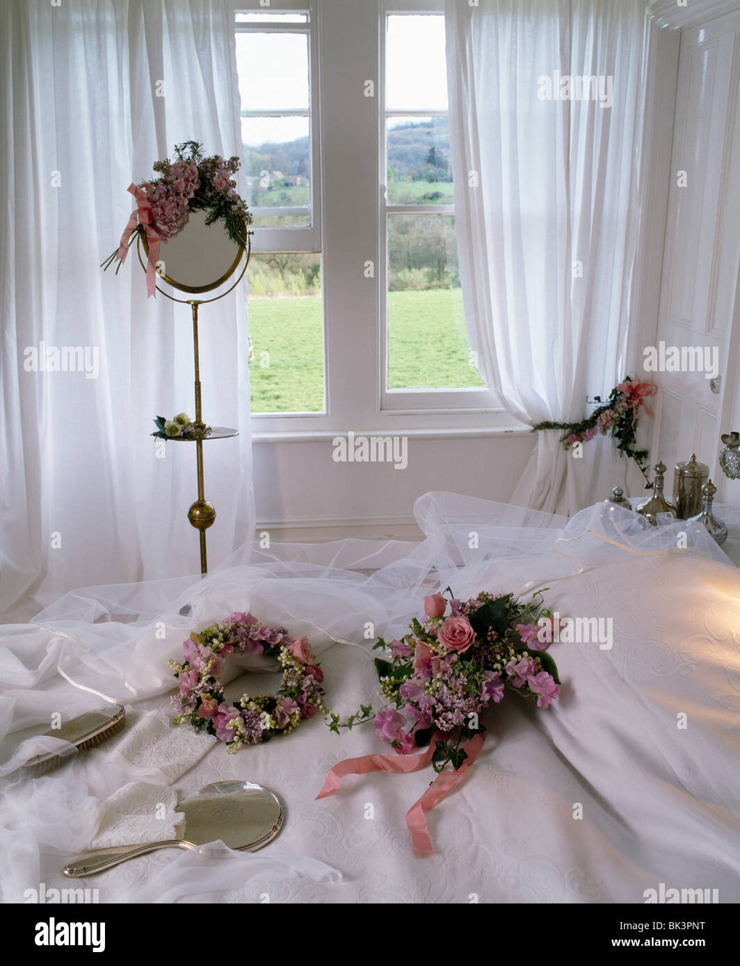 Floral wedding head-dresses and veil on white bed in country bedroom ...