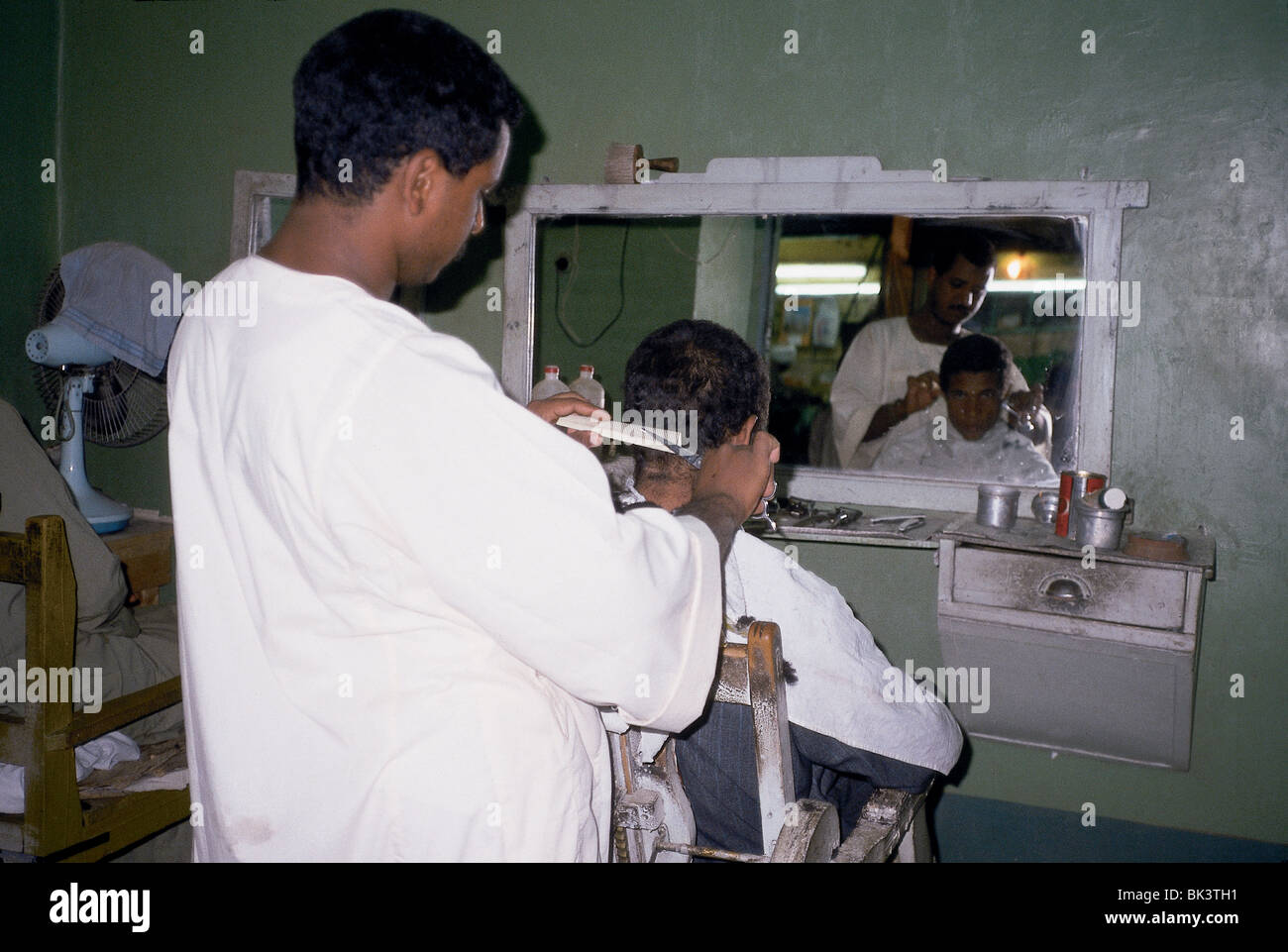 Barber cutting a customer's hair in a barbershop with a mirror, Egypt ...