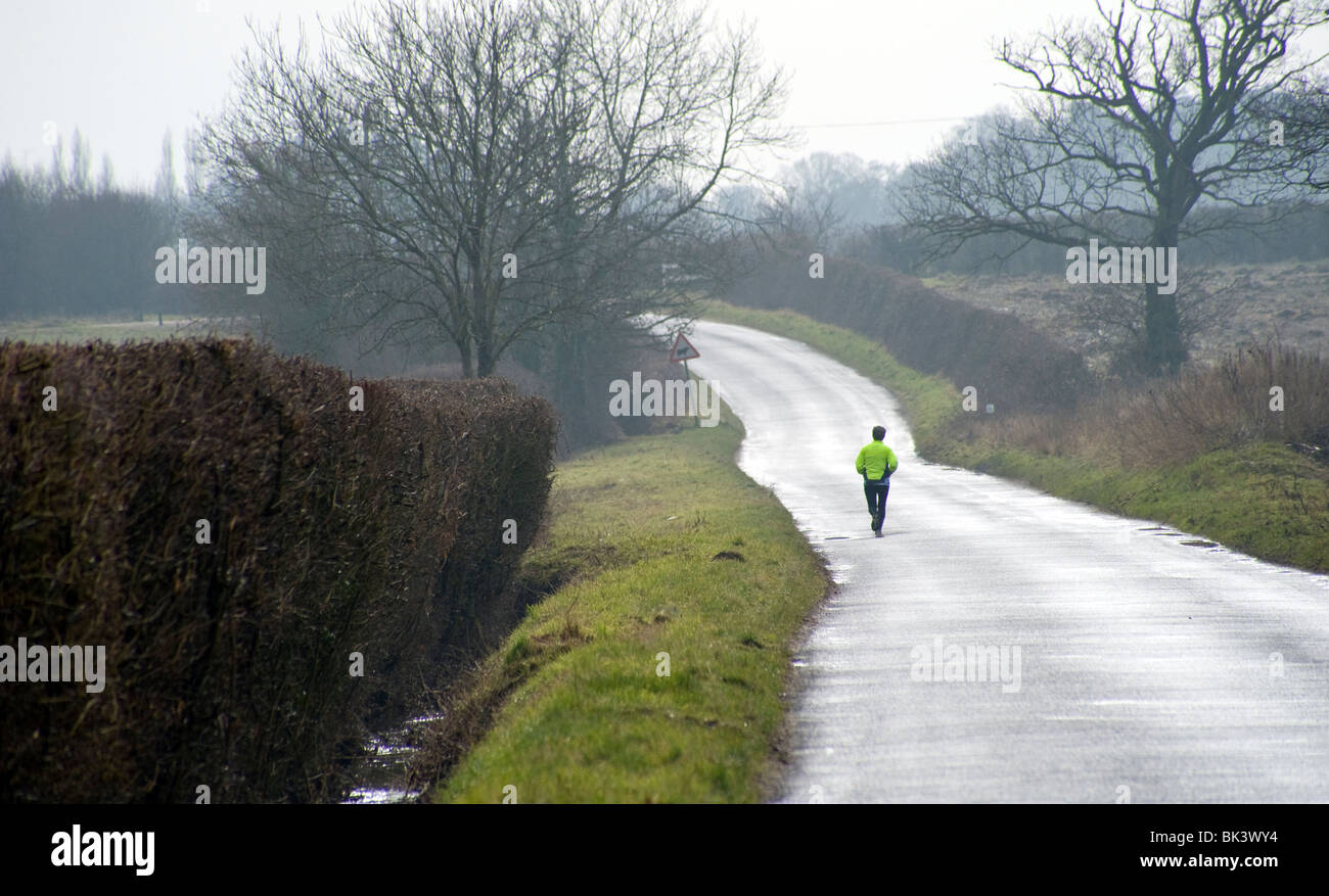 single female runner training for london marathon on empty country road ...