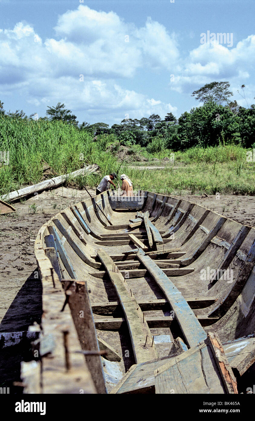 Two men working a homemade dugout boat along the Aguarico River ...