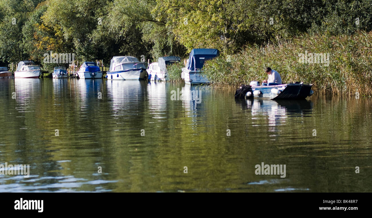 solitary man fishing from dinghy on river waveney at beccles suffolk ...