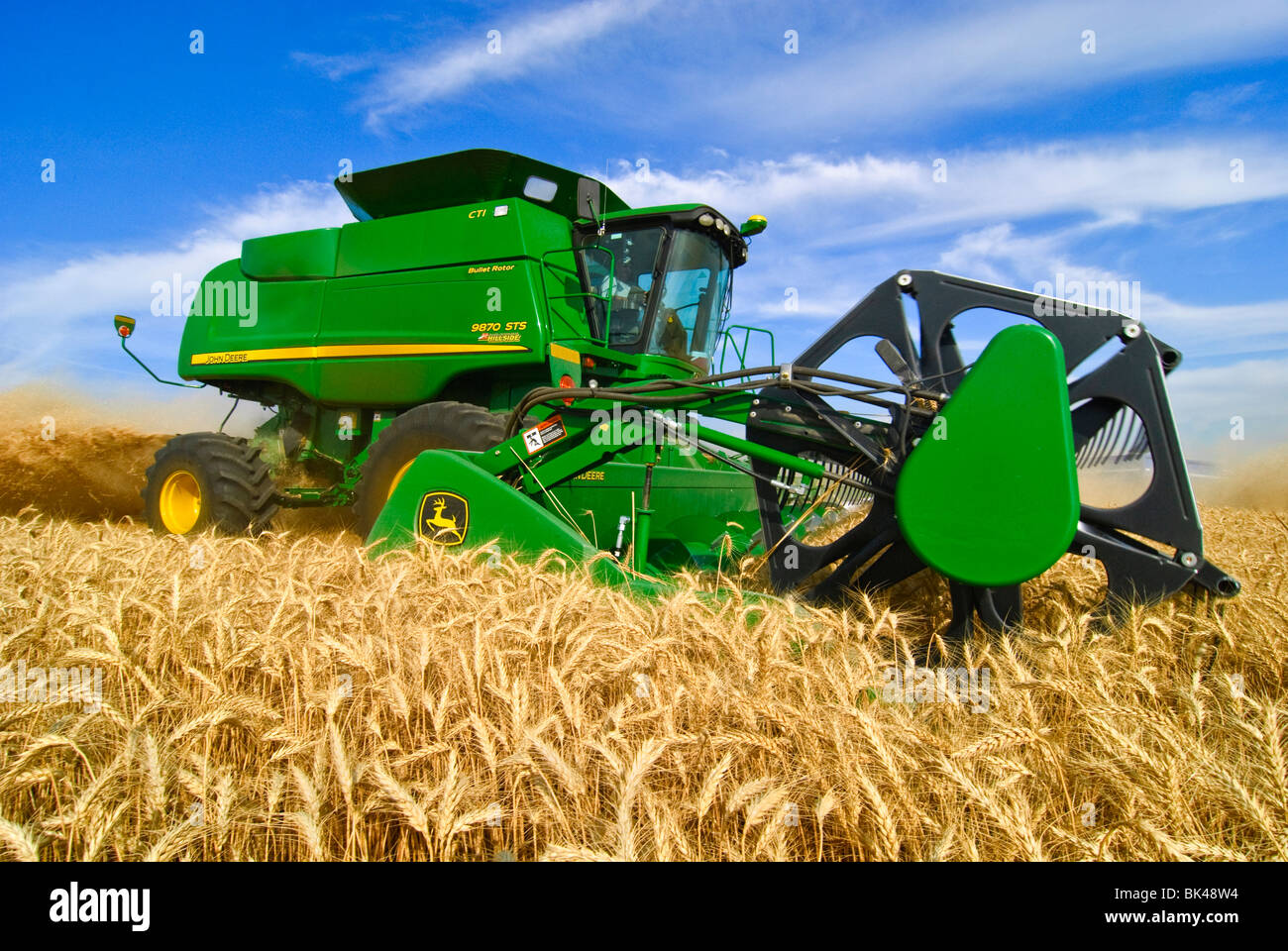 A John Deere combine harvests soft white wheat on the hills of the ...