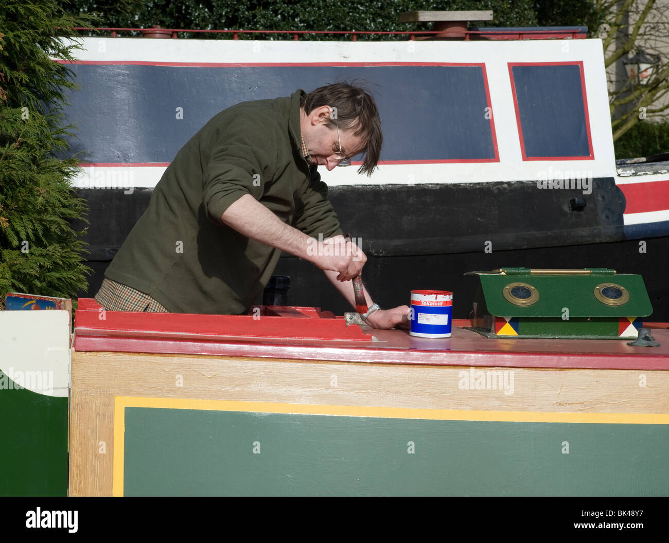 man painting narrow boat hatch Stock Photo - Alamy