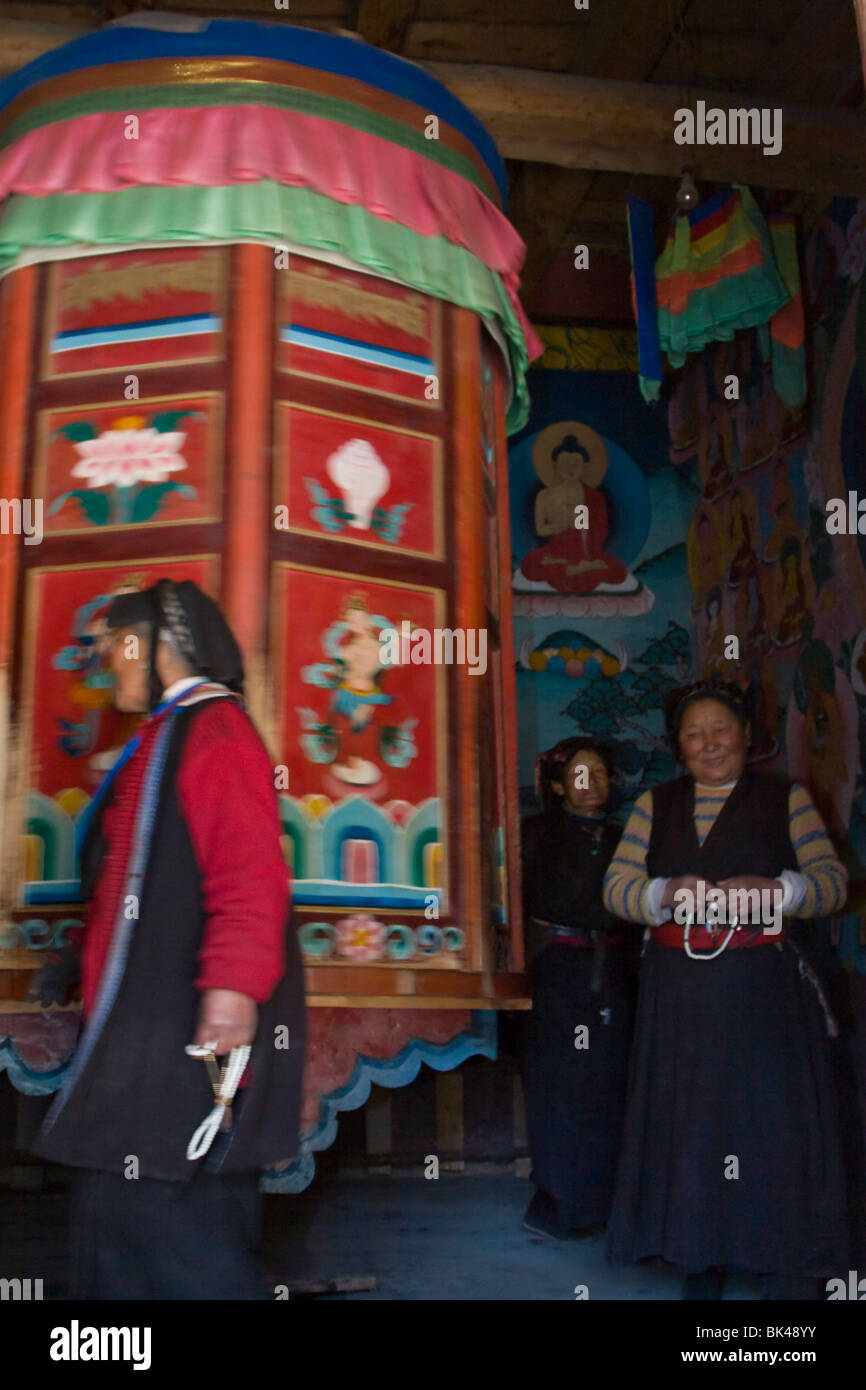 People doing circumambulation around a large prayer wheel in a Tibetan ...