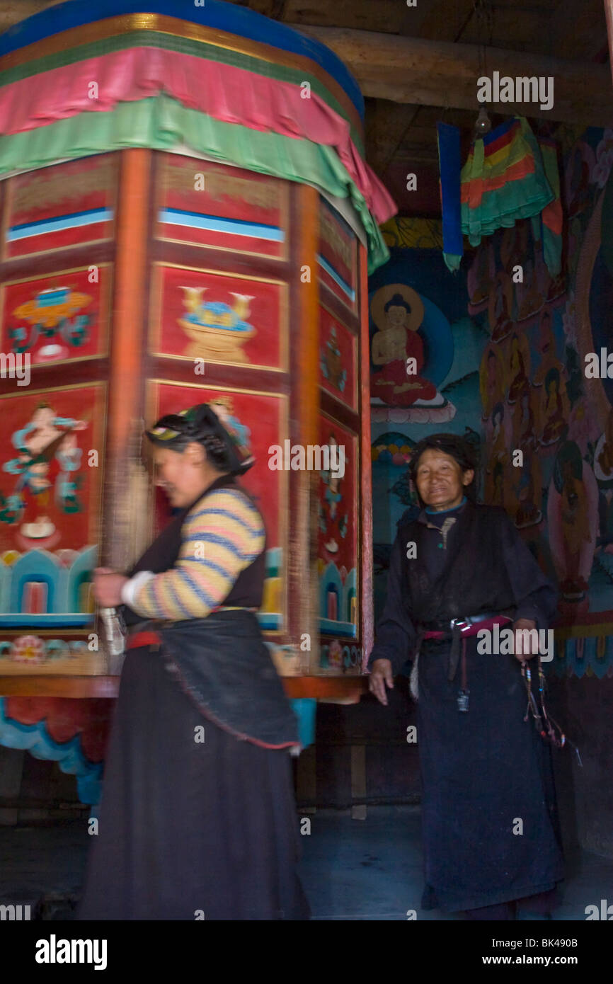 People doing circumambulation around a large prayer wheel in a Tibetan ...