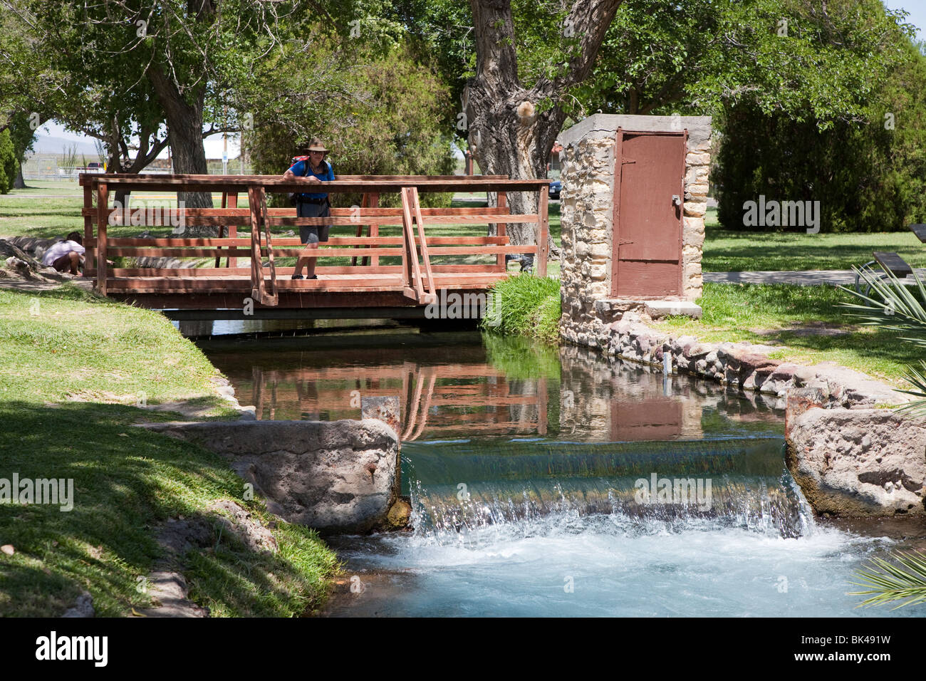 Person standing on bridge at weir in canal fed by San Solomon Springs ...