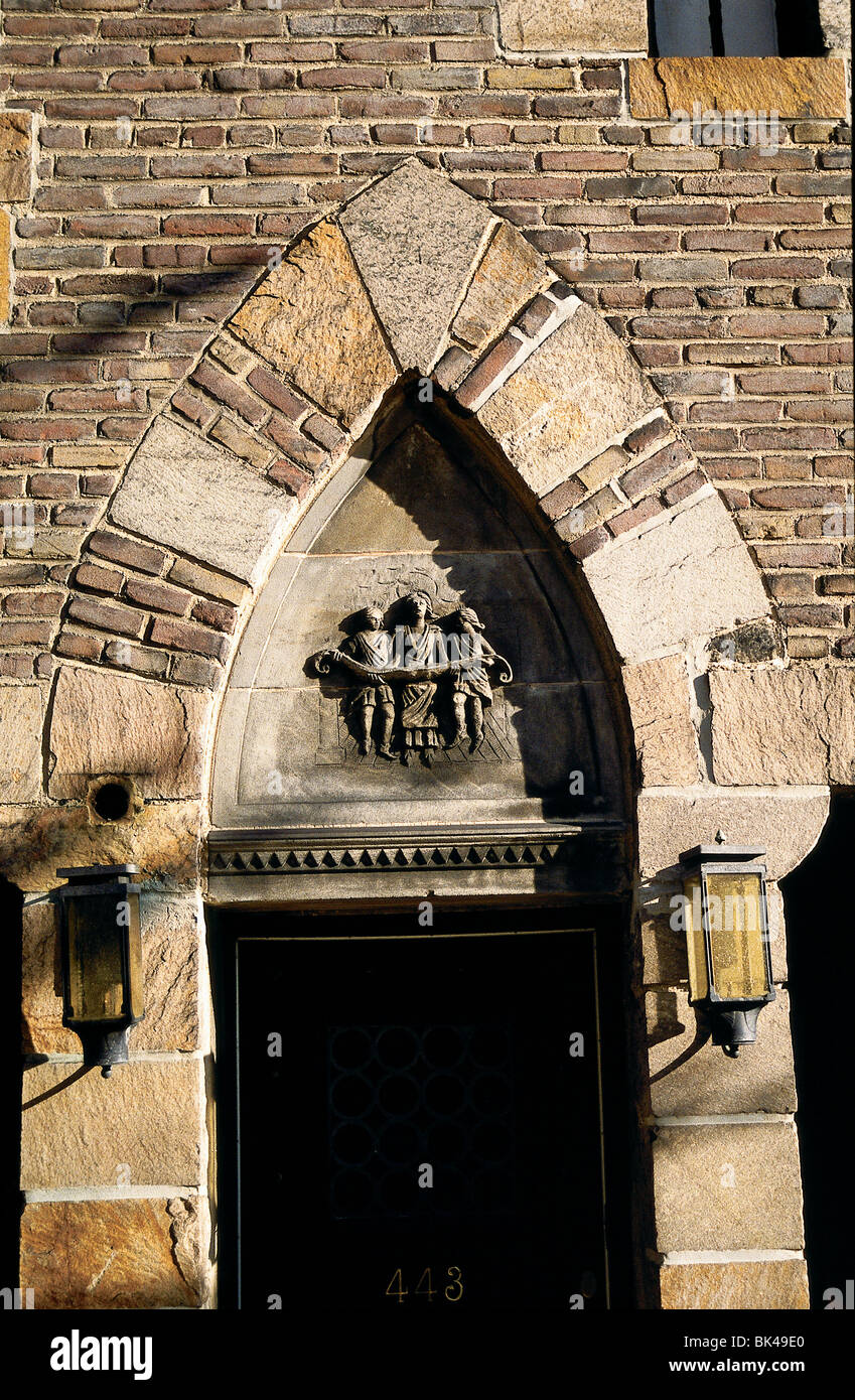 Relief sculpture of three figures below a gothic arch on a brownstone ...
