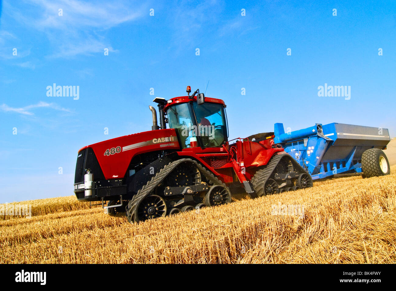 A Case Quad-Trac tractor pulling a grain cart on the hills of a wheat ...