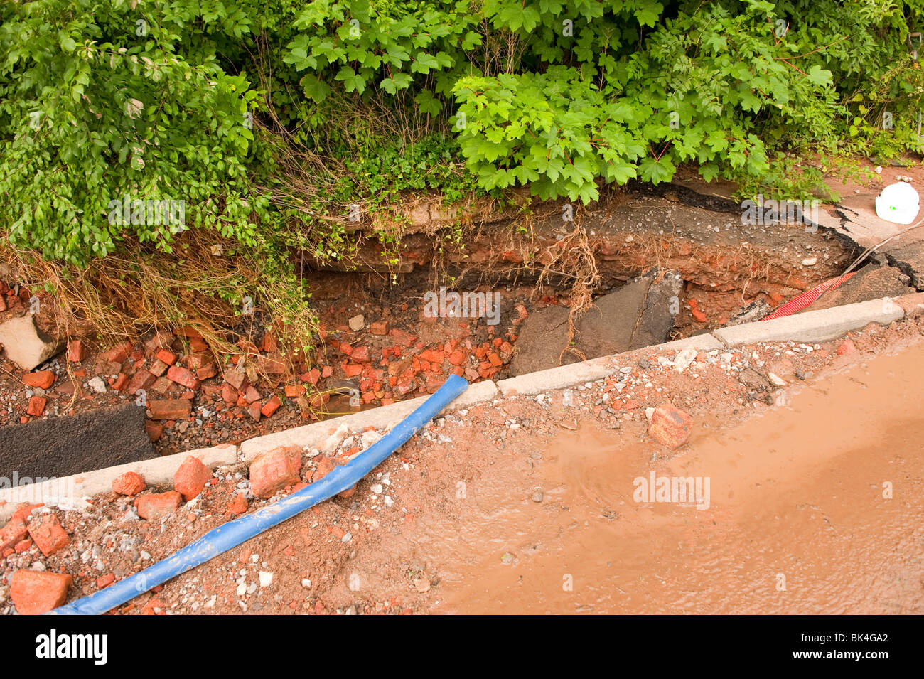 Burst water main pipe washed road and pavement away Stock Photo - Alamy