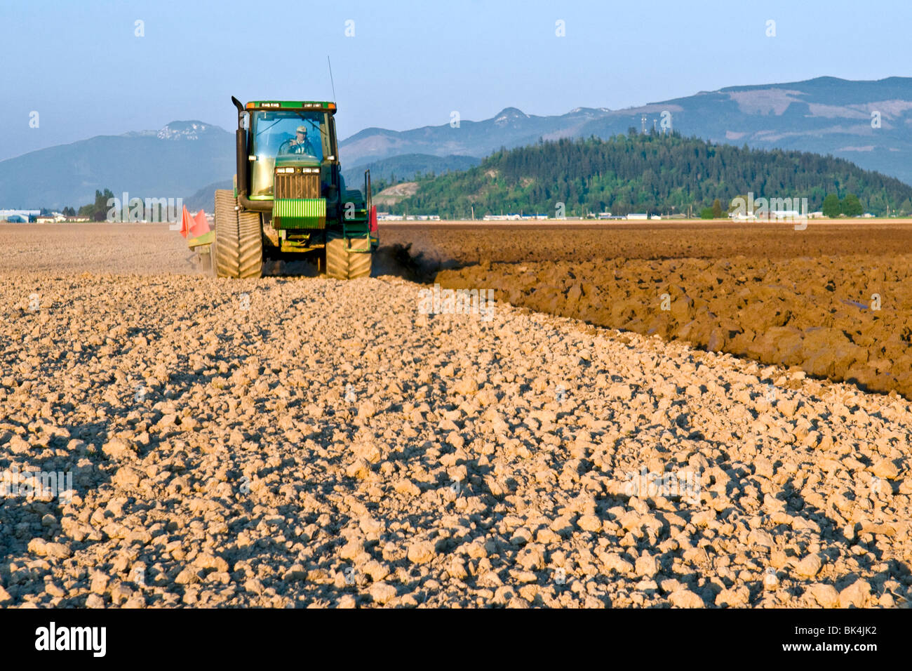 John Deere tractor plowing with reversible plow to prepare the field ...