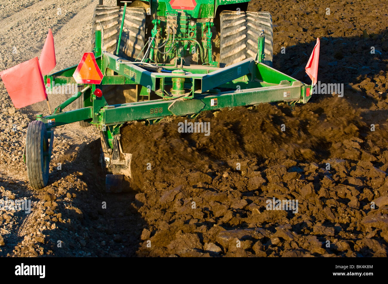John Deere tractor plowing with reversible plow to prepare the field ...