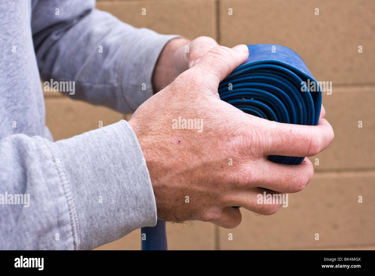 Closeup of man rolling up water hose Stock Photo - Alamy