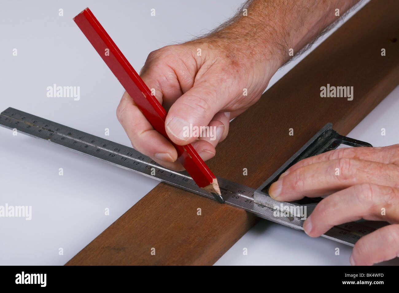A carpenter marking a section of wood using a combination square Stock ...