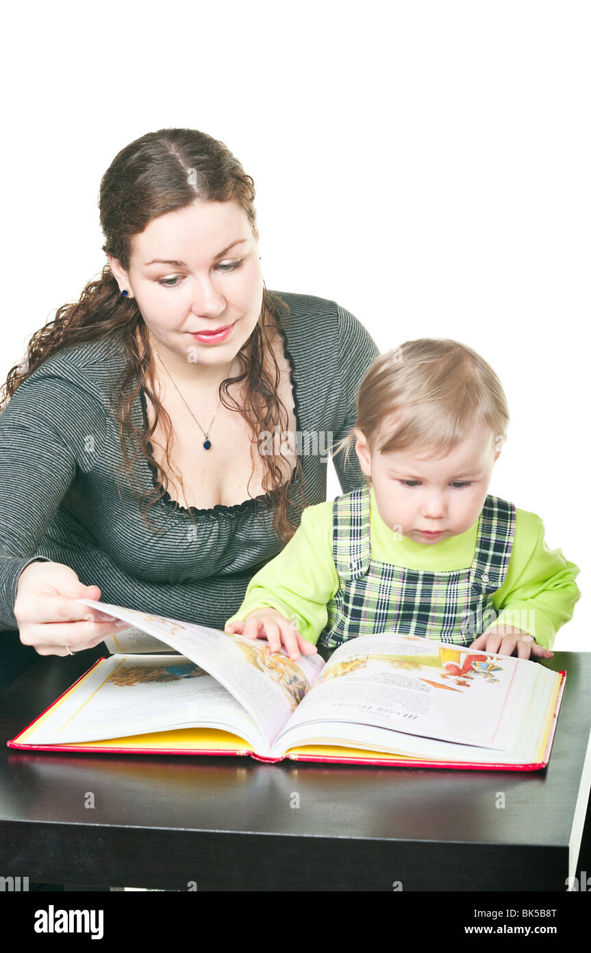 Little child and mother together read the book at a table. It is ...