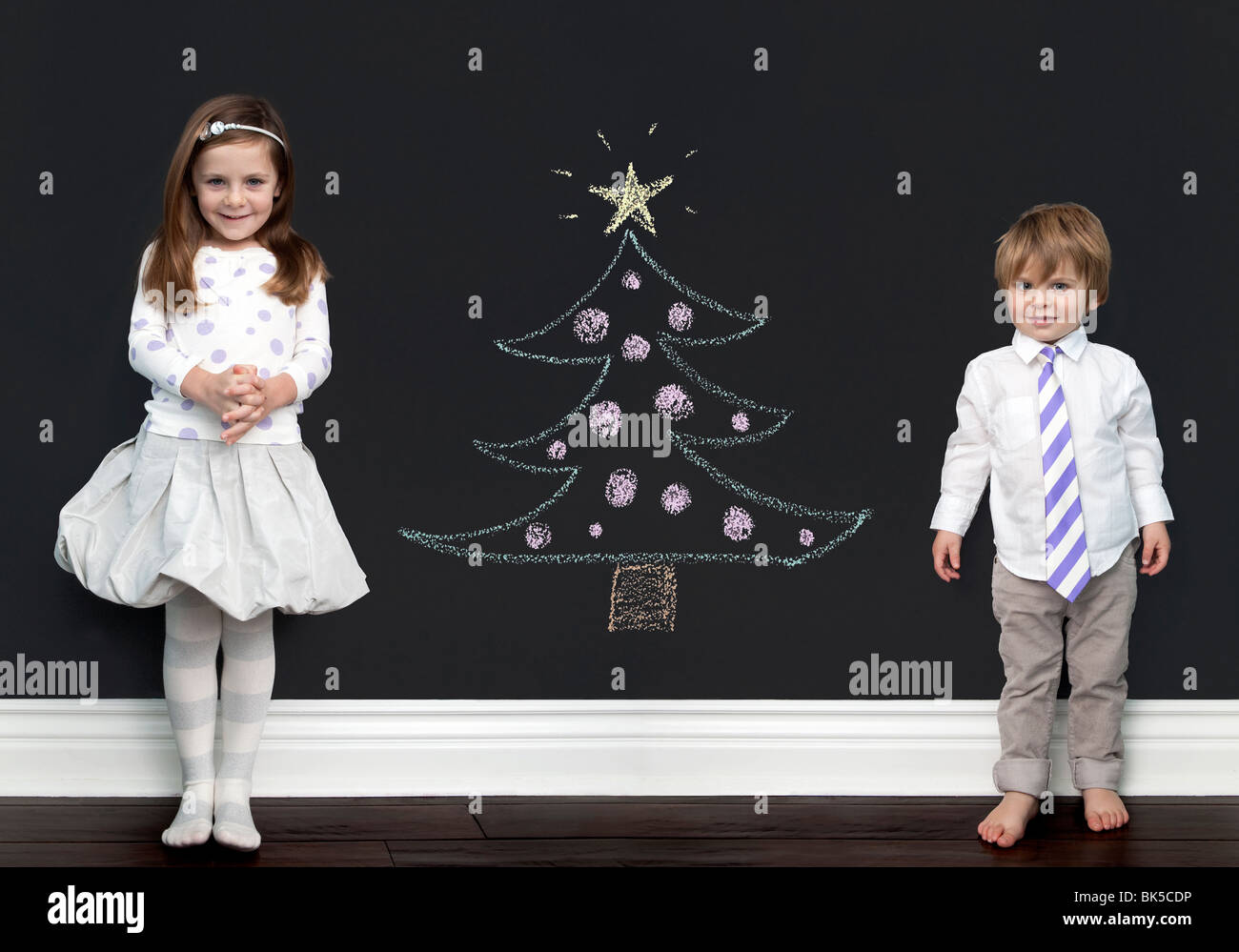 Brother and sister posing by imaginary christmas tree Stock Photo - Alamy