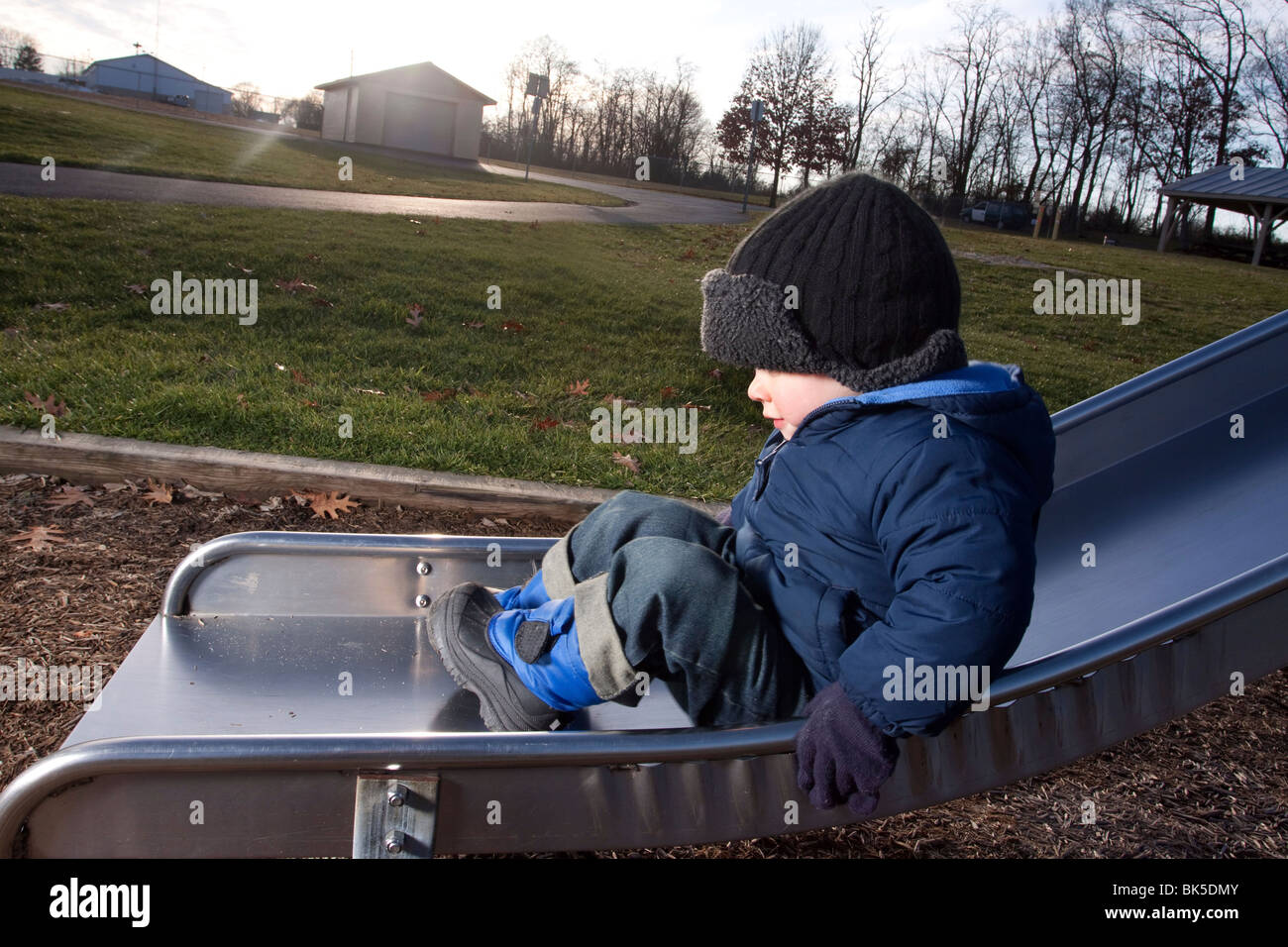 Boy playing on a slide in a park Stock Photo - Alamy
