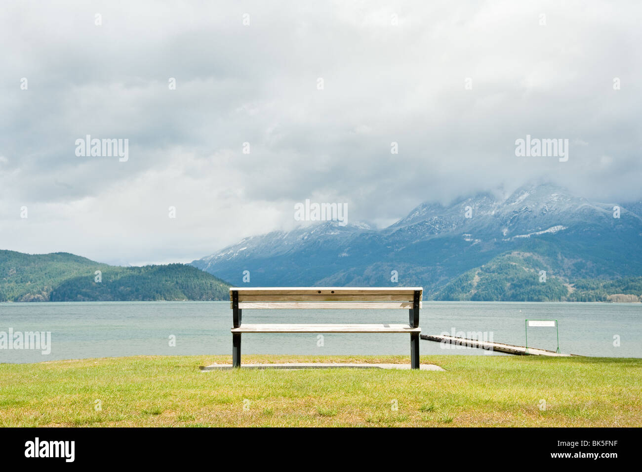 A wooden bench facing a huge and beautiful lake Stock Photo - Alamy