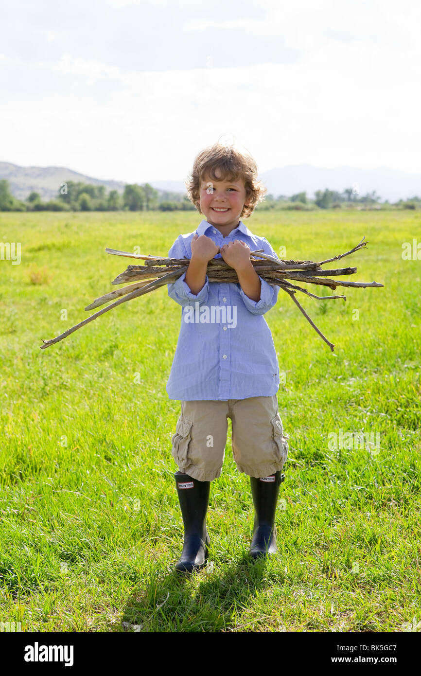 Boy collecting sticks in field Stock Photo - Alamy