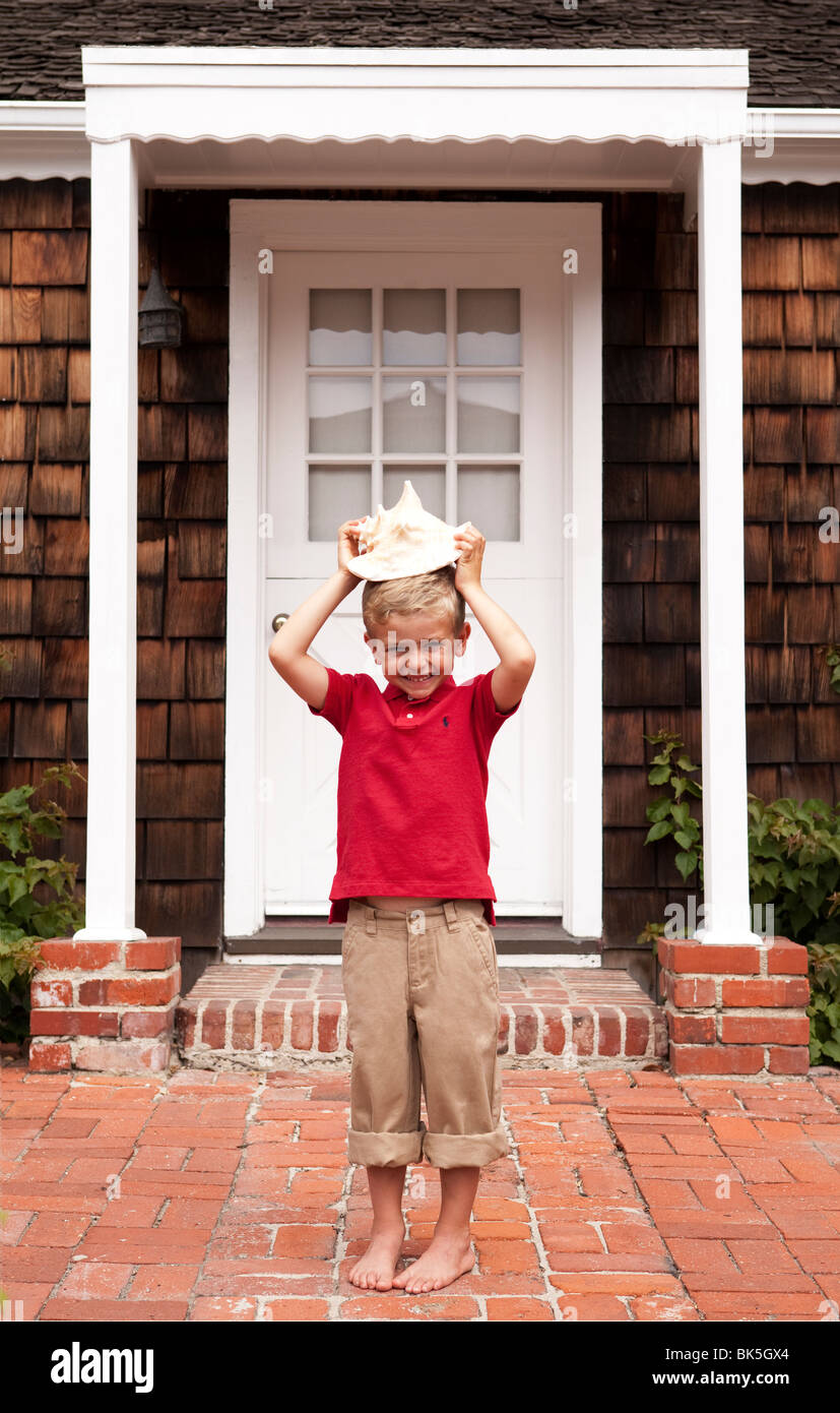 Boy on sidewalk playing with seashell Stock Photo - Alamy