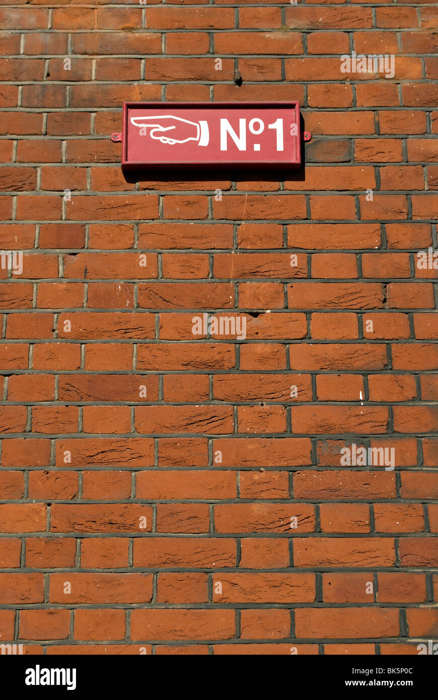 sign on a redbrick wall using image of hand to indicate a number one ...