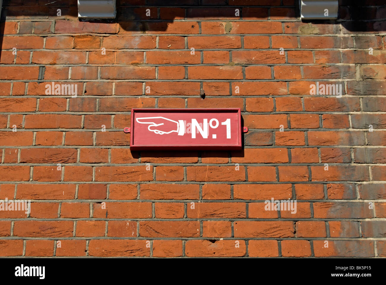 sign on a redbrick wall using image of hand to indicate a number one ...