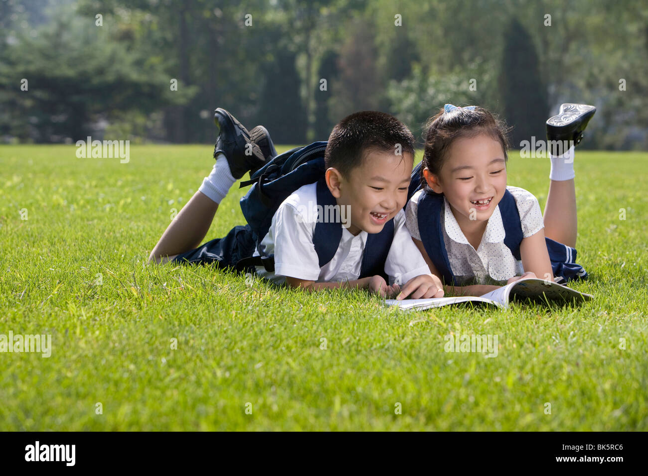Elementary school students reading on the grass Stock Photo - Alamy
