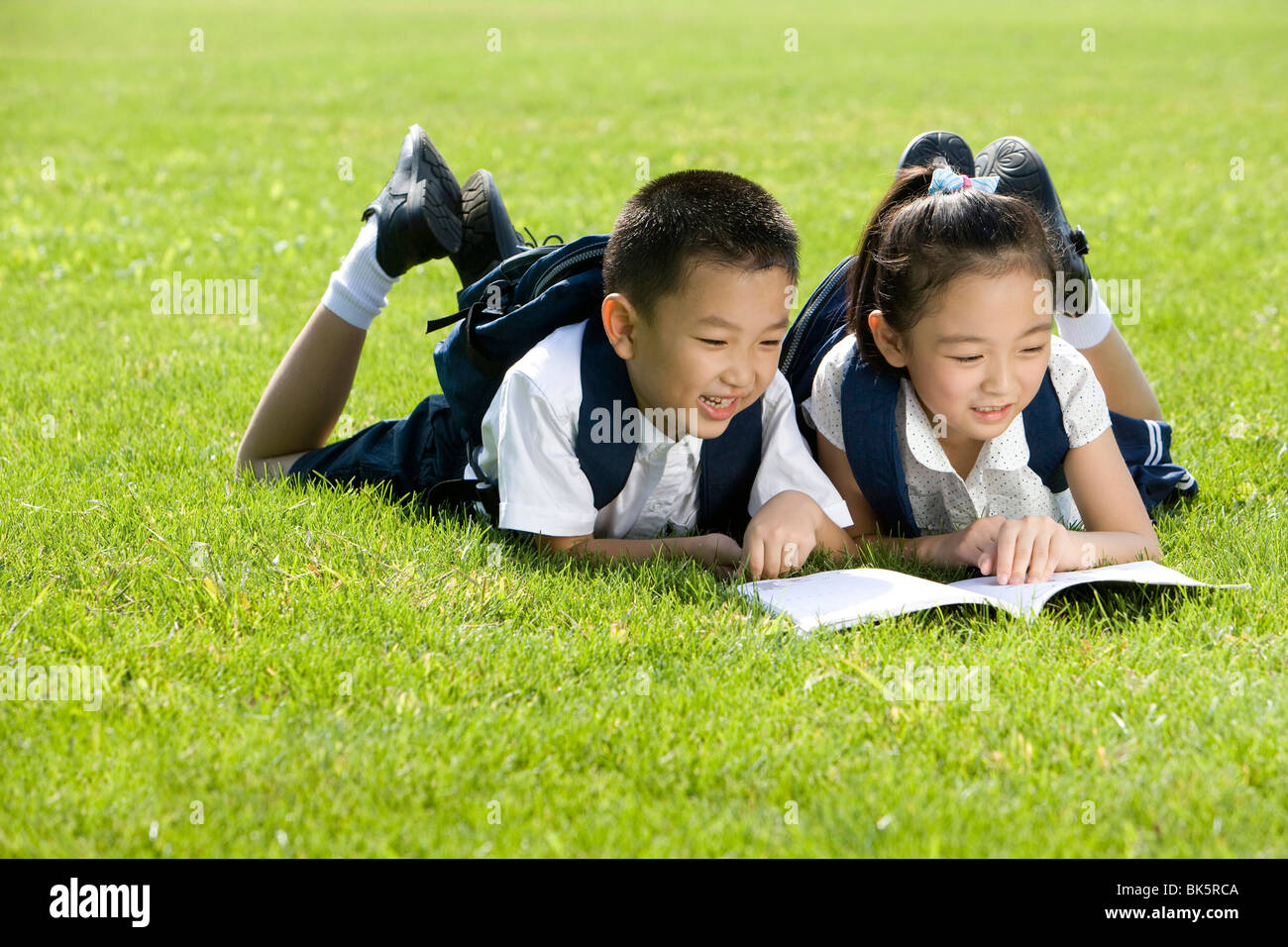 Elementary school students reading on the grass Stock Photo - Alamy