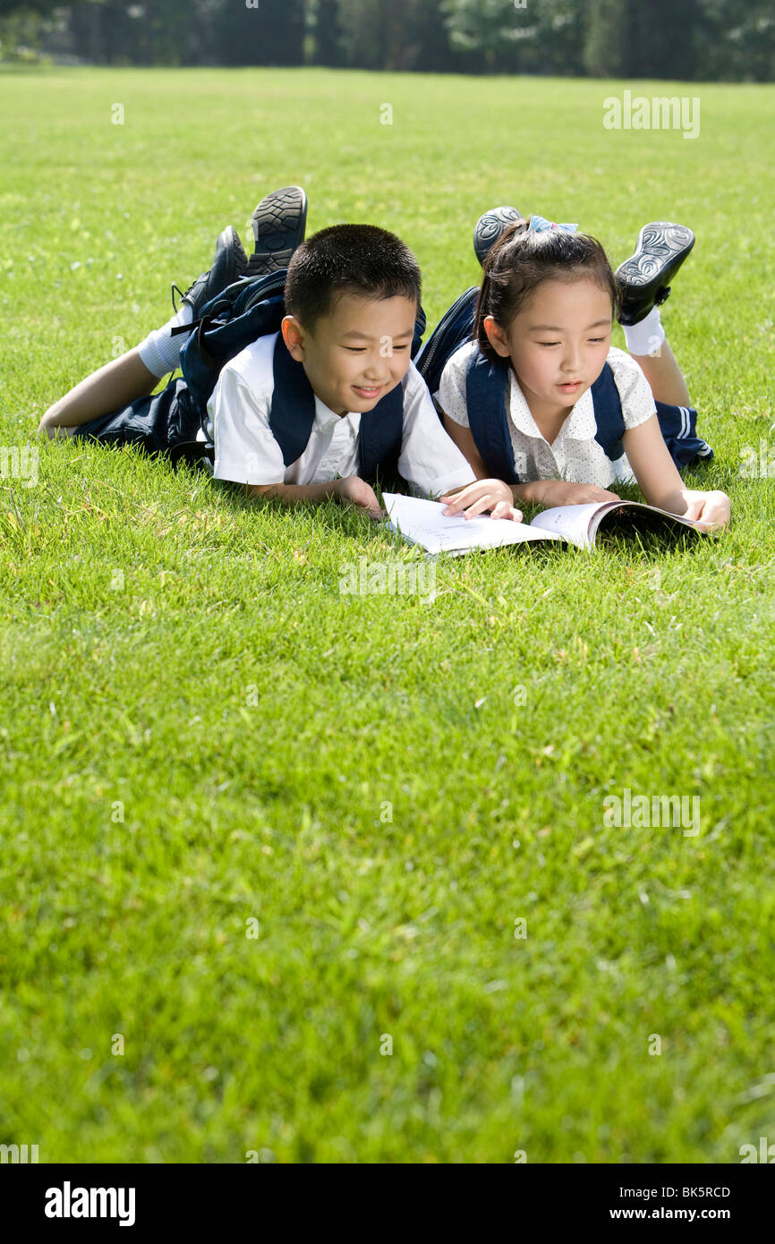 Elementary school students reading on the grass Stock Photo - Alamy