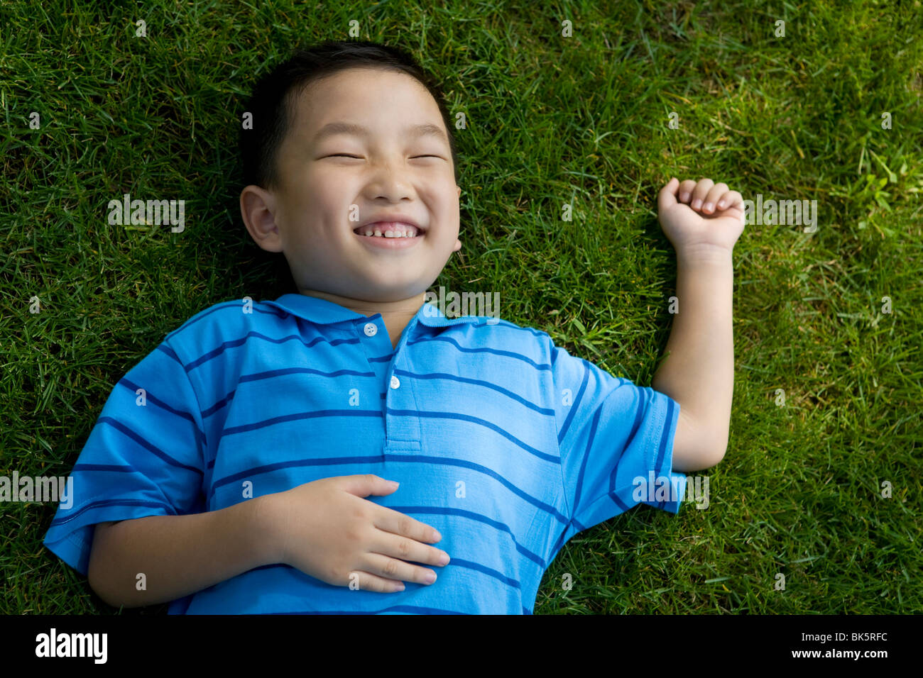 Boy lying on grass arms hi-res stock photography and images - Alamy