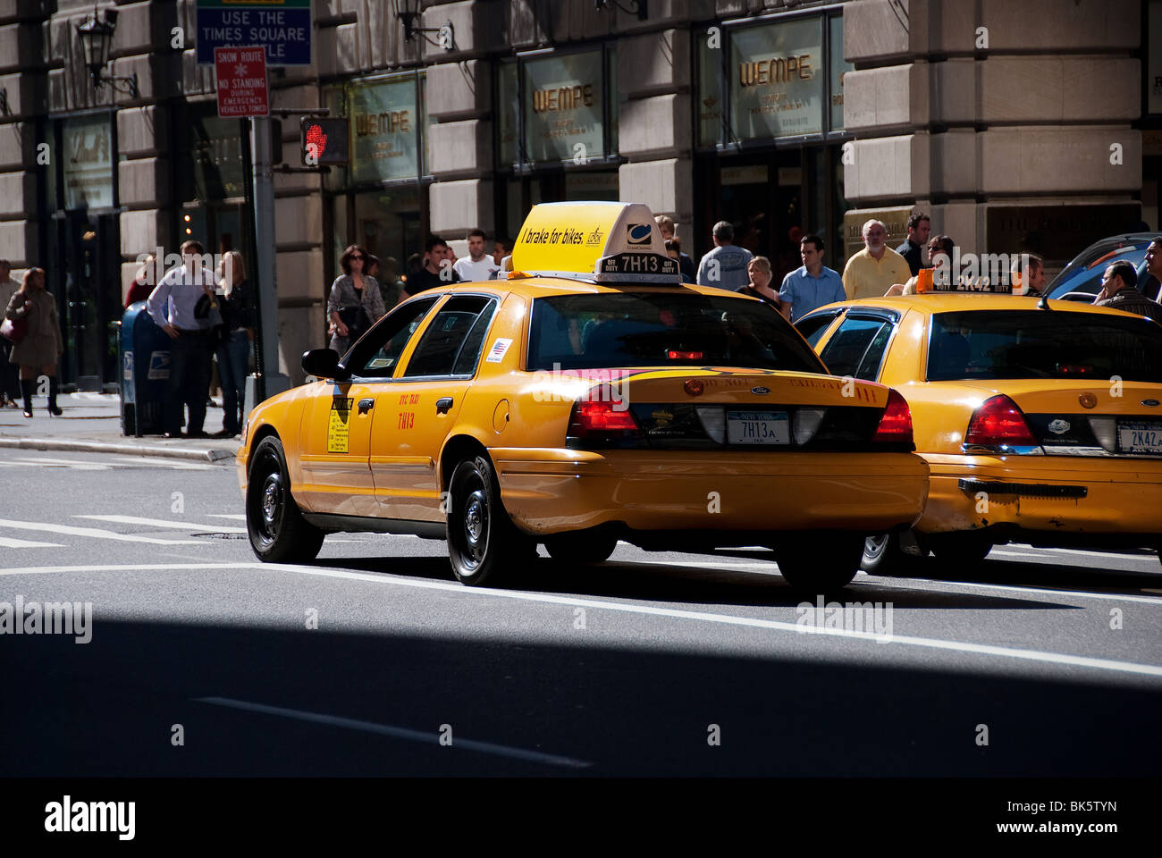 Rear view of two New York Taxis waiting at stop sign in bright sun ...