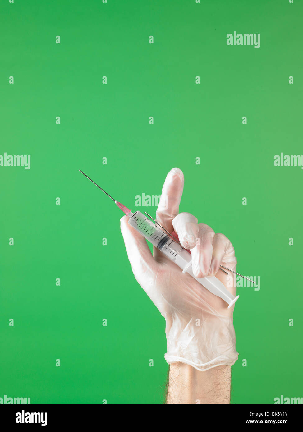 Medical gloved hand with syringe and needles in a half closed hand ...