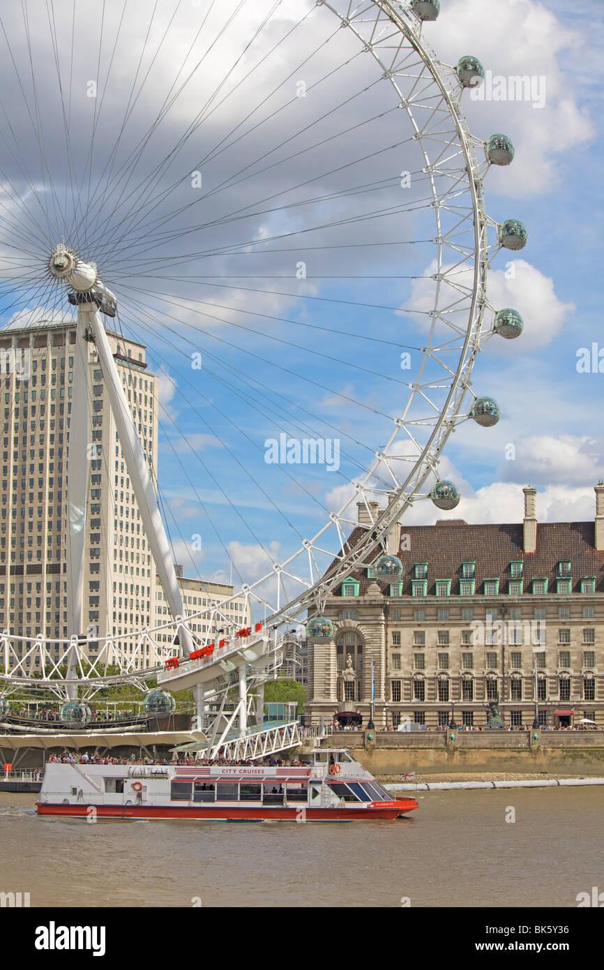 Tourist cruise boat on the River Thames with the London Eye in the ...