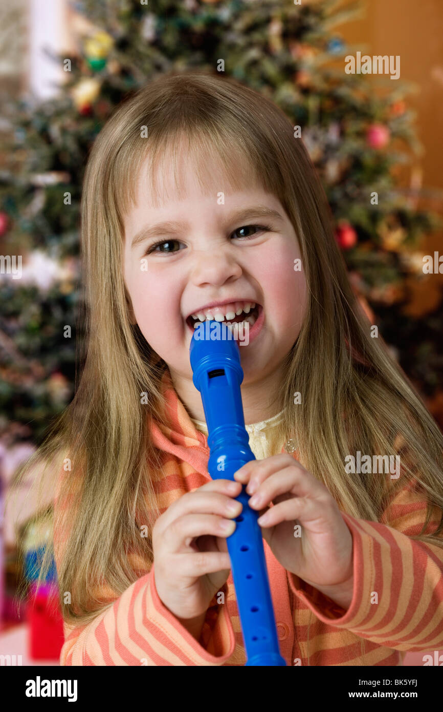 Girl playing a recorder in front of Christmas tree Stock Photo - Alamy