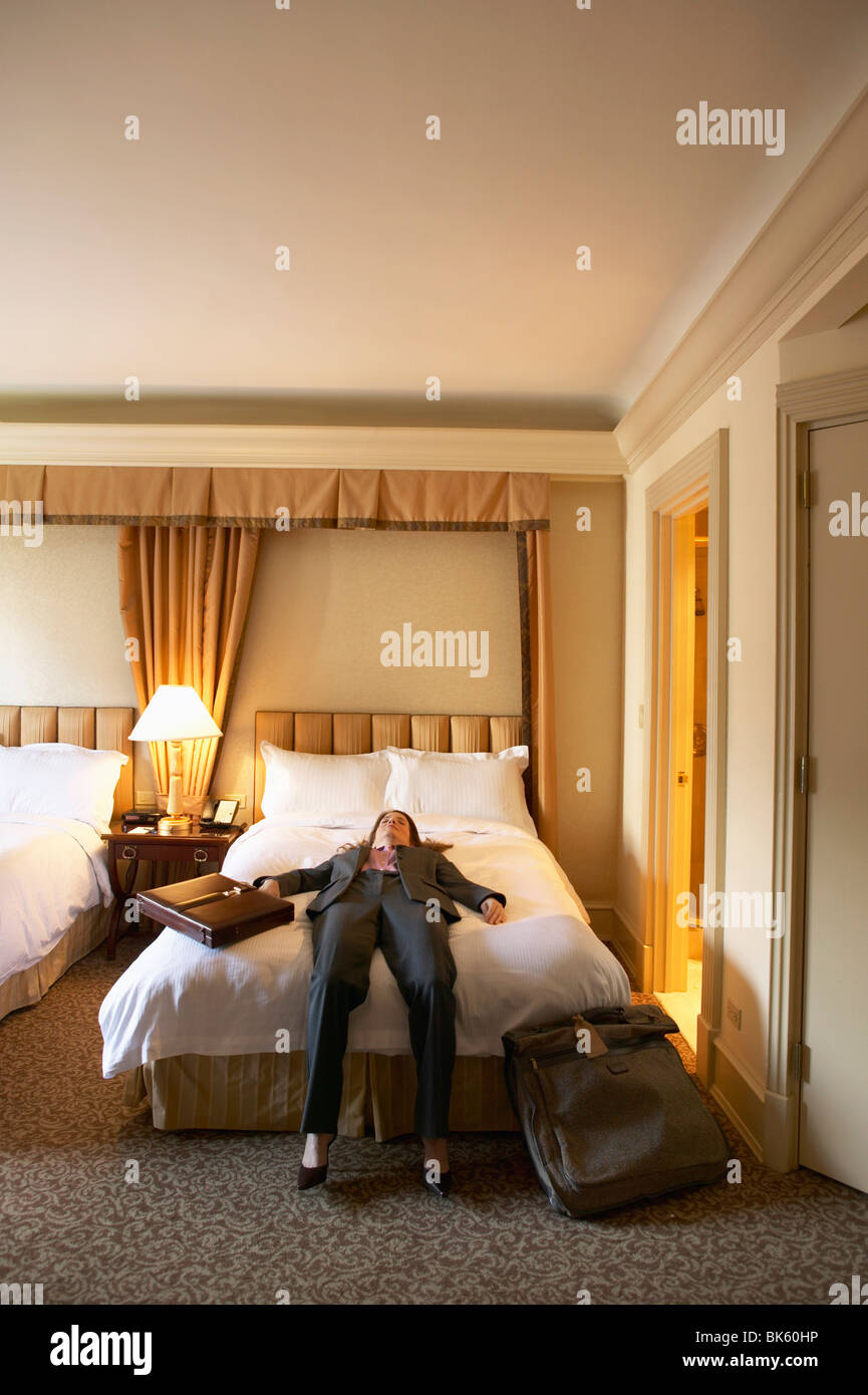 Businesswoman lying on the bed in a hotel room Stock Photo - Alamy