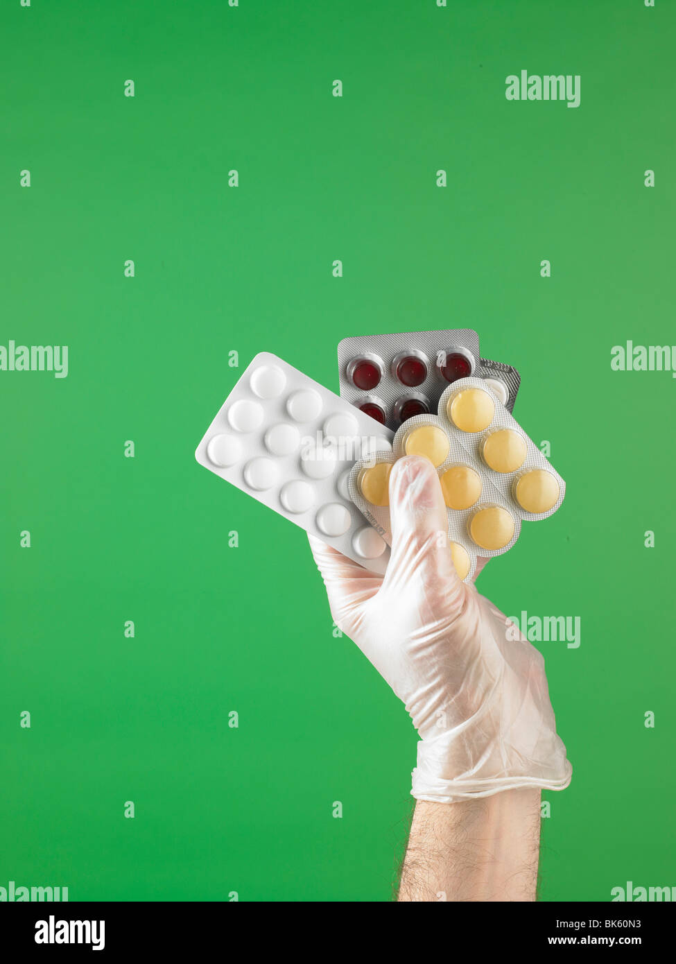 Gloved hand with drugs and pills on a green background Stock Photo - Alamy