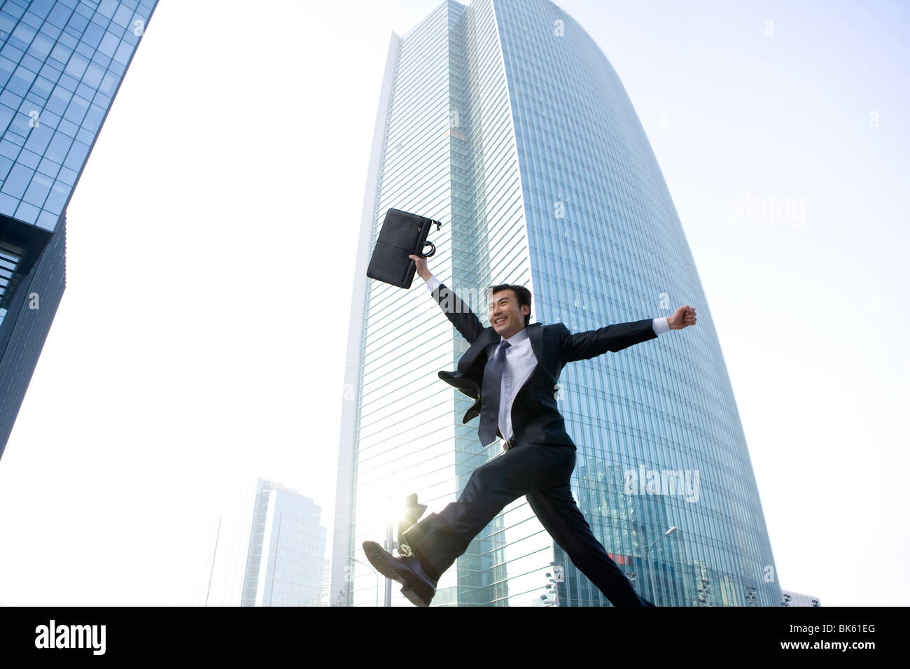 Businessman jumping in front of tall building Stock Photo - Alamy