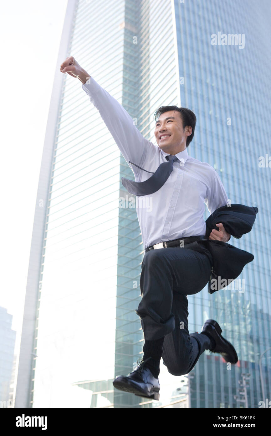 Businessman jumping in front of tall building Stock Photo - Alamy